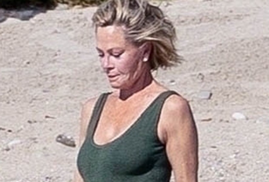 De maiô, Melanie Griffith se refresca em praia no Caribe