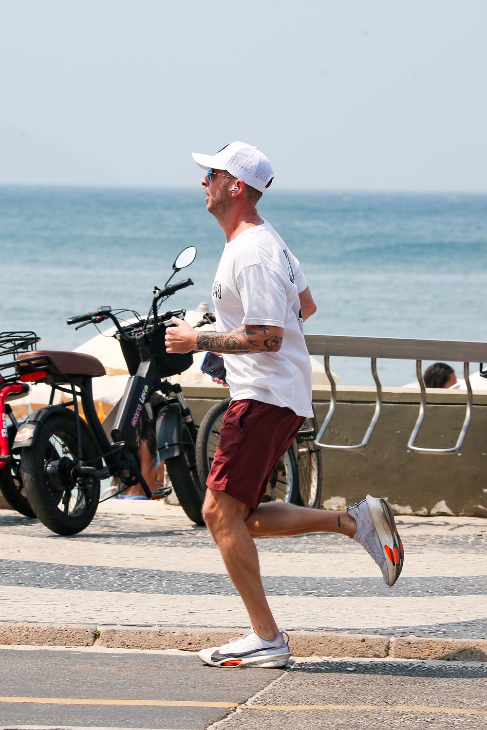 Ryan Tedder, do OneRepublic, corre com o celular na mão em orla antes ...