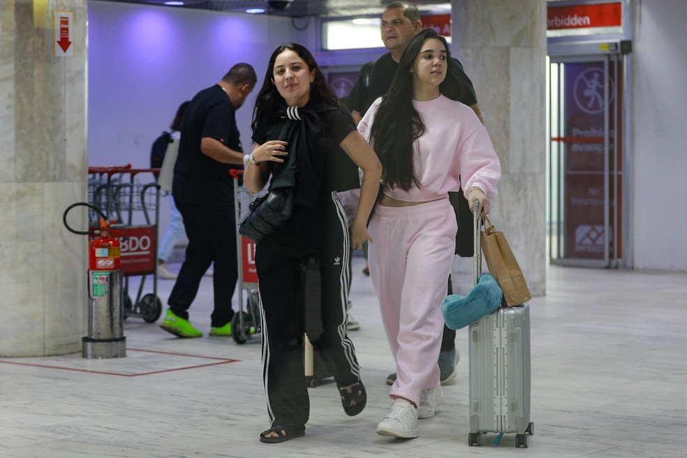 De mãos dadas, Mari Fernandez e Júlia Ribeiro desembarcam no aeroporto do Rio de Janeiro
