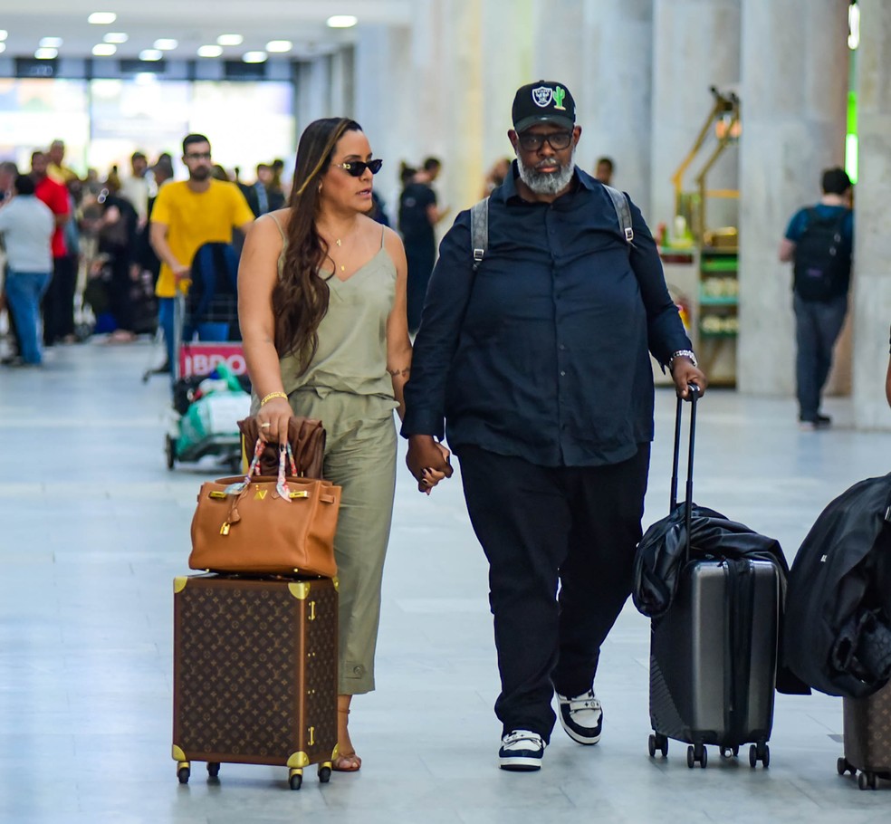 Com mala de R$ 58 mil, Péricles faz rara aparição com a esposa em aeroporto