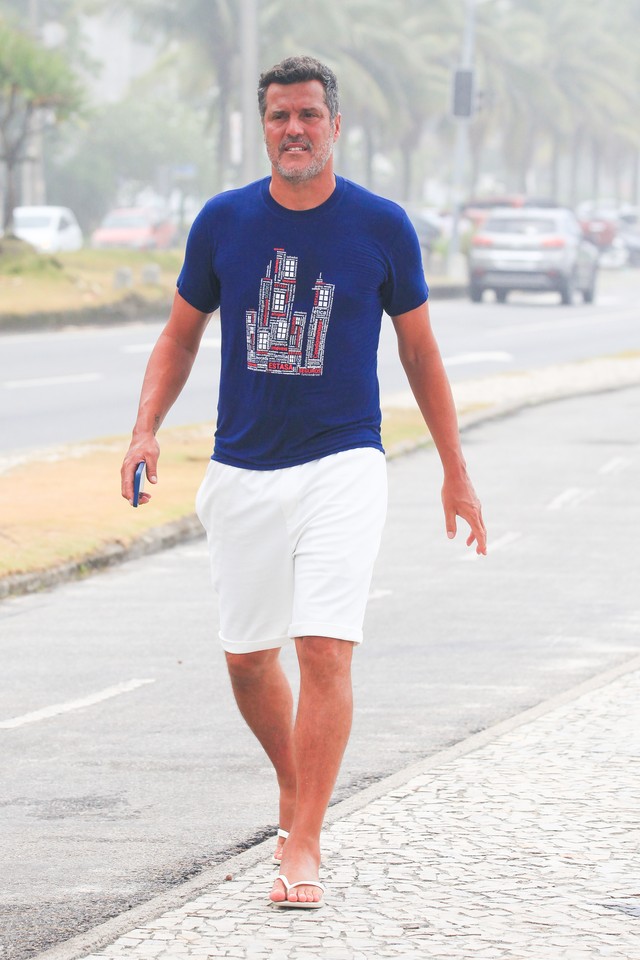 Solteiro, Julio Cesar caminha pela orla da Barra da Tijuca em dia nublado