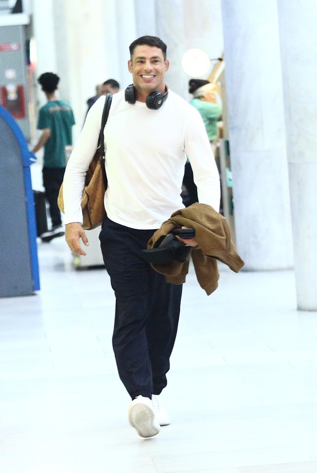 Cauã Reymond posa sorridente após desembarcar em aeroporto do Rio