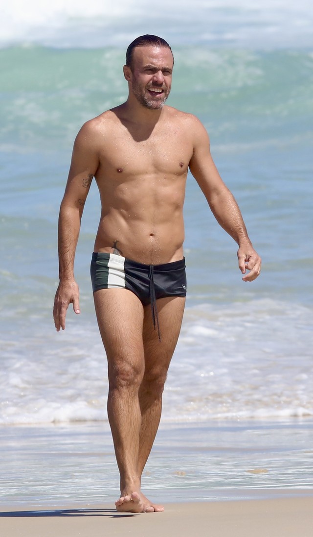 Roger Flores exibe abdômen definido em dia de praia com cachorro