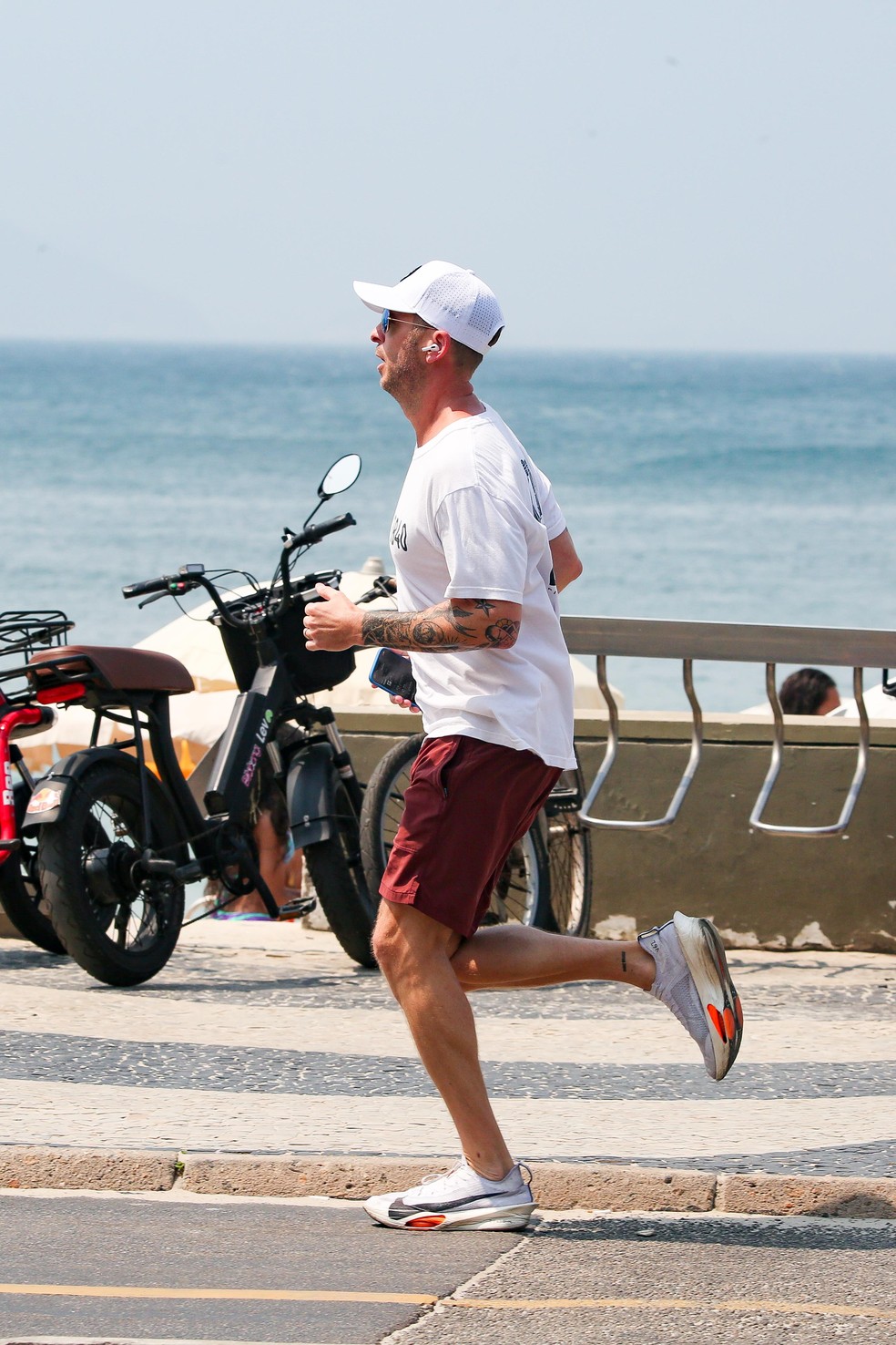 Ryan Tedder, do OneRepublic, corre com o celular na mão em orla antes ...