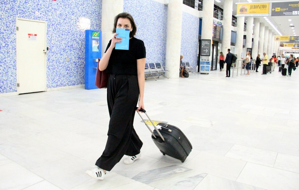 De visual novo, Monica Iozzi esconde rosto em chegada a aeroporto no Rio